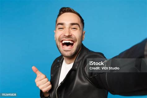 까만 가죽 자 켓 흰색 T셔츠 파란색 벽 배경 스튜디오 초상화에 고립 된 찾고 세련 된 젊은 얼굴을 가진 남자의 셀 카를 닫습니다 사람들은 진지한 감정 개념입니다 복사