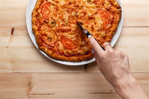 수 제 피자를 절단 하는 사람 손 나무 테이블에는 커터와 수 제 피자를 자르는 손 최고 볼 수 있습니다 평면 배치 건강에 좋지 않은 음식에 대한 스톡 사진 및 기타 이미지