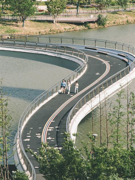 가족 산책 강가 강가의 강둑 강변 걷고 있는 사람 걷는 길 경치 경치가 좋은 고요한 곡선 다리 곡선형 디자인 공공 장소 공원 풍경 나무가 늘어선