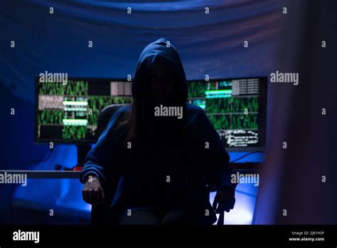 Hooded Anonymous Hacker By Computer In The Dark Room At Night Cyberwar