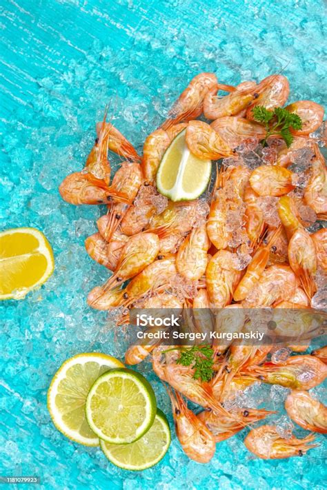 머리가 없는 붉은 신선한 새우 랑구스틴 얼음 푸른 바다 배경 체리 레몬과 라임 조각이 둥근 슬라이스 신선한 허브 빛 상단 측면
