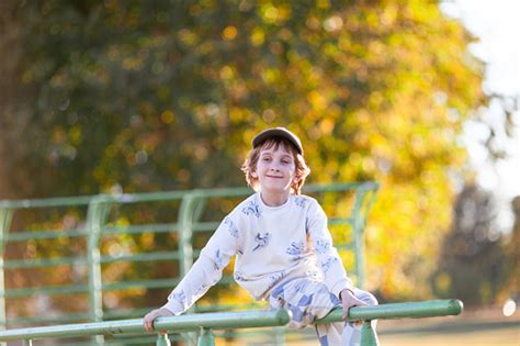 어린이 놀이터의 수평 막대에 앉아 있는 긍정적인 소년 행복한 아이는 산책을 즐깁니다 어린이와 스포츠 공간 복사 6 7 살에 대한