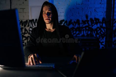 Portrait Of Hidden Hacker Man Wearing Sweatshirt With Hood Engaged In Hacking Into Security