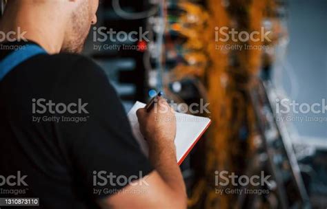 손에 메모장이있는 유니폼을 입은 젊은 남자는 서버 룸에서 인터넷 장비 및 전선으로 작동합니다 25 29세에 대한 스톡 사진 및 기타 이미지 Istock