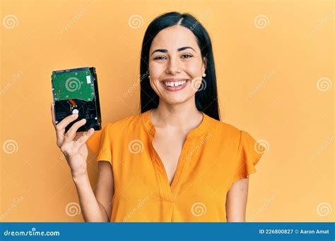 Bella Joven Sosteniendo Un Disco Duro Con Aspecto Positivo Y Feliz De Pie Y Sonriendo Con Una