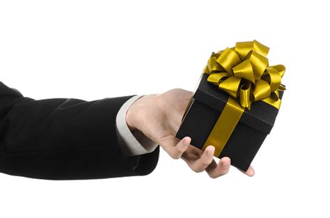 축 하와 선물의 테마 독점 선물 골드 리본 및 활 스튜디오에서 흰색 배경에 고립 된 가장 아름 다운 선물 블랙 박스에 포장을 들고 검은 양복에 남자 검은색에 대한 스톡 사진