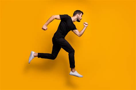 잘 생긴 밀레니엄 남자의 전체 길이 프로필 사진 점프 높은 돌진 낮은 가격 할인 쇼핑 착용 검은 색 티셔츠 바지 고립 된 노란색 색상 배경 T 셔츠에 대한 스톡 사진 및