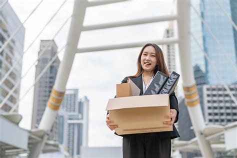 매력적인 젊은 아시아 여성 신선한 대학 졸업생은 방콕의 중앙 비즈니스 지구에서 새로운 직업을 제안 한 후 행복하고 안도감을 느끼는 개인 소지품 상자를 들고 있습니다 20