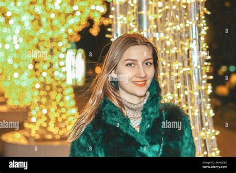 Young Pretty Girl In Green Fur Coat Outdoor On The Glowing Background