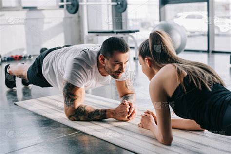 男性私人教练和运动员在健身房做木板