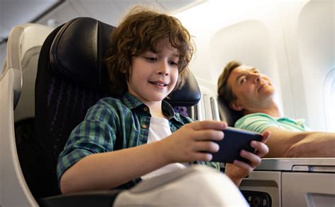 비행기로 여행 하 고 휴대 전화에 온보드를 게임 행복 한 소년 비행기에 대한 스톡 사진 및 기타 이미지 비행기 스마트폰 지켜 봄 Istock