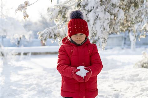 겨울에 눈으로 노는 아기 빨간 재킷을 입은 어린 유아 소년과 크리스마스 에 겨울 공원에서 눈송이를 잡는 크리스마스 순록 니트 모자 아이들은 눈 덮인 숲에서 놀고 있습니다
