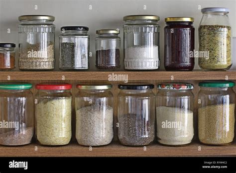 Various Food In Reused Produce Glass Jars On A Kitchen Shelf Stock