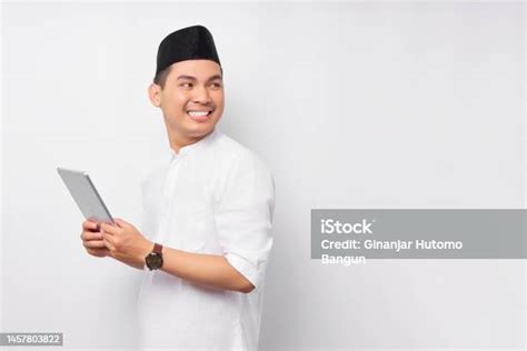 웃고 있는 젊은 아시아 무슬림 남성이 디지털 태블릿을 들고 흰색 배경에 격리된 빈 복사 공간을 보고 있다 사람들은 종교적인 이슬람 생활 방식 개념입니다 축하 라마단과 Ied