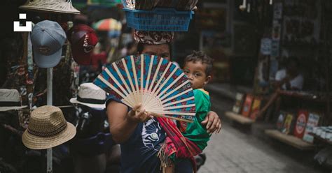 손 선풍기를 사용하여 얼굴을 숨기는 아기를 안고 있는 여자 사진 Unsplash의 무료 우붓 이미지