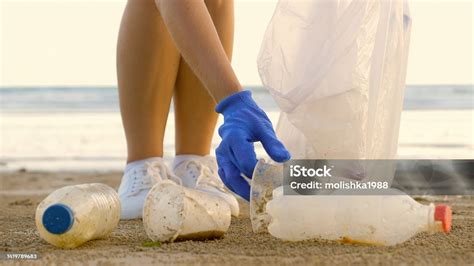 해변에서 플라스틱으로 모래 사장을 청소하는 여성 자원 봉사자들은 쓰레기 봉투에 쓰레기를 모은다 해양 플라스틱 오염 자연 환경