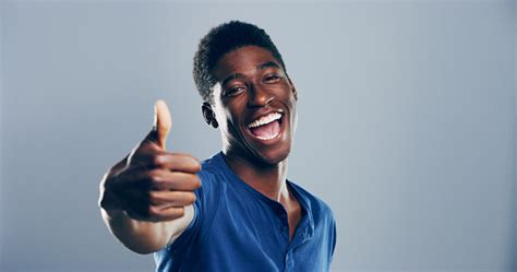 행복한 흑인 남자와 회색 스튜디오 배경에서 승리 성공 또는 좋은 직업에 대해 엄지 손가락을 치켜 올리는 초상화 얼굴 남성 또는 미소가 있는 모델예 이모티콘 또는 모형 공간에