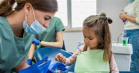 젊은 자격을 갖춘 전문 치과 의사 여성이 리셉션에 데려 온 어린 아이의 치아를 닦고 있습니다 아기 치아 칫솔질의 개념 사진 Unsplash의 아기 인간 나이 이미지