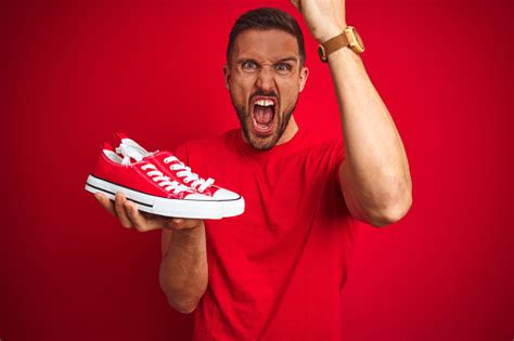 빨간 고립 된 배경에 캐주얼 운동화 신발을 들고 젊은 남자는 짜증과 분노와 함께 고함 미친 고함 제기 손으로 소리 분노 개념 감정에 대한 스톡 사진 및 기타 이미지 Istock