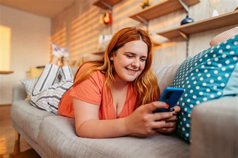 집에서 스마트 폰으로 소셜 미디어를 확인하는 젊은 여성 과체중에 대한 스톡 사진 및 기타 이미지 과체중 소파 한 명의