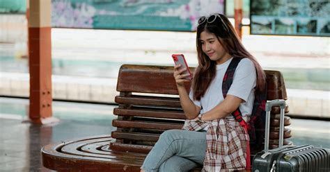 아시아 여자는 기차역에서 기차를 기다립니다 여행 개념입니다 온라인 여행 계획을 위해 스마트 폰을 사용하는 여행자 사진 Unsplash의 태국 이미지