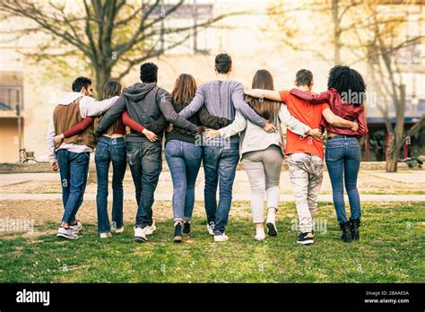 Group Of Young Multiracial People Walking Arm Around Shoulders Outdoors