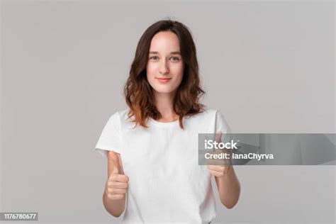 회색 배경 위에 고립 된 긍정적 인 평가를 표현하는 엄지 손가락을 들고 흰색 티셔츠에 예쁜 갈색 머리 여자 마음에 듭니다 십대 소녀에 대한 스톡 사진 및 기타 이미지