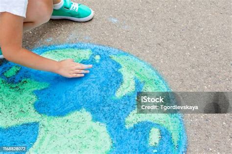 아이 소녀는 아스팔트에 색깔분필로 세계의 행성을 그립니다 어린이 그림 그림 및 개념 교육과 예술 당신이 학교에 돌아갈 때 창의력 지구 평화의 날 지구본에 대한 스톡 사진 및