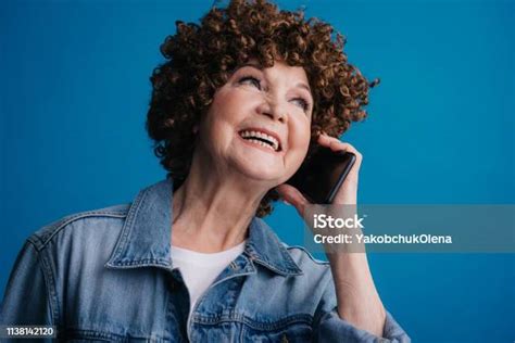 스튜디오에서 스마트 폰에 이야기 하는 즐거운 노인 여자의 낮은 각도 갈색 머리에 대한 스톡 사진 및 기타 이미지 갈색 머리 곱슬 머리 나이 Istock