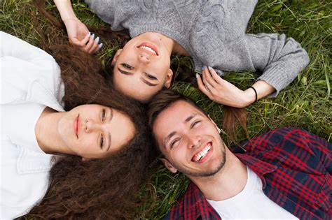 Premium Photo Two Girls And Guy Lying On Grass