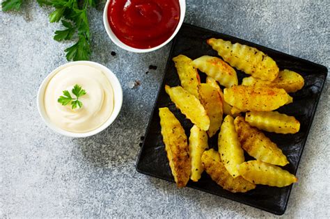 패스트 푸드 향신료를 곁들인 구운 감자 슬레이트 또는 스톤에 슬라이스 마요네즈와 케첩 소스와 함께 제공됩니다 평평한 배경의 맨 위 보기입니다 공간을 복사합니다 0명에 대한