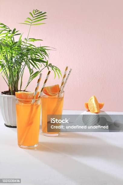 긴 하드 섀도우 최소한의 해독 다이어트 개념 수직 방향 여름 비타민 음료 핑크 배경에 대한 스탠드와 연단에 감귤류 오렌지 주스와 오렌지와 현대 정물 생활 0명에 대한 스톡