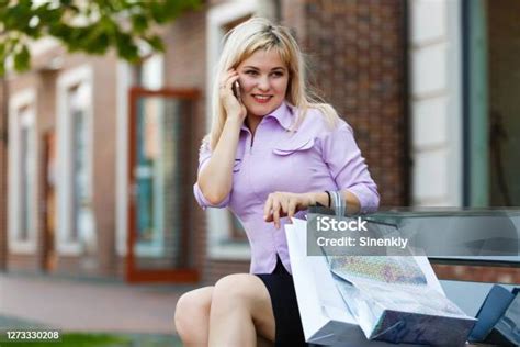 벤치에 예쁜 여자와 쇼핑 후 큰 쇼핑몰에서 전화로 이야기 셔츠 스커트 안경 하이힐을 입은 매력적인 여성 많은 쇼핑백이 근처 벤치에 있습니다 20 29세에 대한 스톡 사진 및