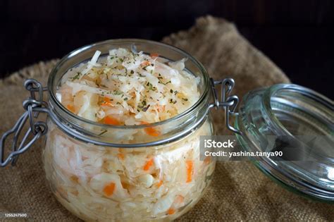 검은 색 배경에 유리 항아리에 허브와 당근과 클로즈업 홈 메이드 소금에 절인 양배추 나무 테이블에 자루가 있는 양배추절임 통조림 식품의 개념 복사 공간을 복사합니다 채식