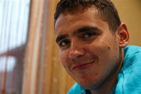 실내에서 웃고 있는 젊은 갈색 머리 백인 남자의 초상화를 흐리게 한다 사춘기 테마 문제성 피부 십대 여드름 순수한 피부를 가진 잘 생긴 남자가 얼굴을 만지고 있습니다 초점이