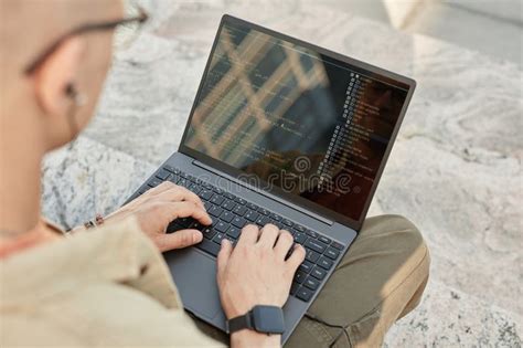 Male Software Developer Writing Code On Laptop While Sitting On Steps Outdoors Stock Image