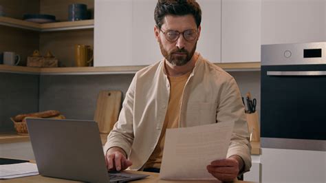 백인 남성 남편 세입자 집주인 웹 사이트에서 온라인으로 청구서 지불 앱 서류 작업 계획 예산 재정 노트북 컴퓨터 사용 부엌에서 모기지 지불 프리랜서 집에서 문서 작업