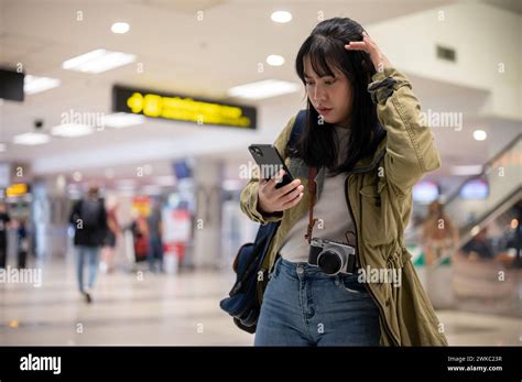 A Confused Young Asian Female Solo Traveler Is Reading Her Flight