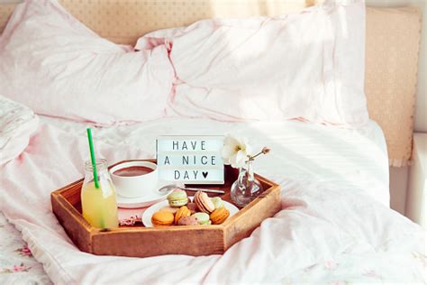 침대와 아침 식사는 좋은 하루 텍스트 조명된 상자에 커피 주스 마카롱 컵 나무 쟁반에 꽃병에 꽃 좋은 아침 분위기입니다 환대 의료 서비스 개념입니다 공간에 복사 합니다