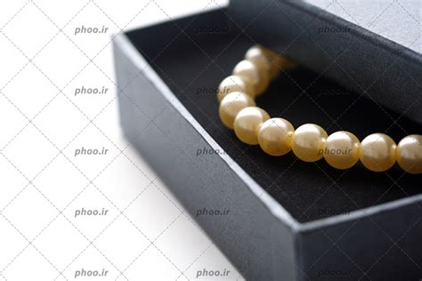 عکس گردنبندی از مروارید در جعبه مشکی در پس زمینه سفید عکس با کیفیت و تصاویر استوک حرفه ای