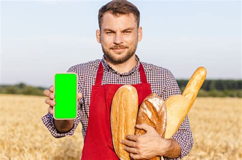 베이커 남자는 손에 빵 덩어리를 들고 휴대 전화의 화면을 보여줍니다 35 39세에 대한 스톡 사진 및 기타 이미지 35 39세 곡초류 공란 Istock