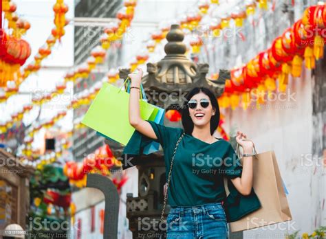 아시아 여성은 쇼핑 또는 쇼핑 중독은 복사 공간과 흐림 도시 또는 관광 배경 부드러운 톤과 할인 시즌 동안 다채로운 종이 쇼핑백과 함께 올드 타운에서 쇼핑에 중독이 된다