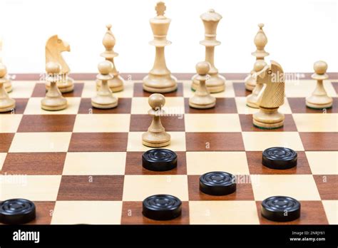 Playing By Different Rules On The Same Board Black Checkers And White Chess Figures On Wooden