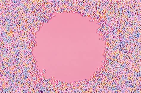 분홍색에 파스텔 컬러 볼로 만든 둥근 프레임 스티로폼 또는 폴리스티렌 폼 배경 과자 장식을위한 다채로운 설탕 공의 혼합 무지개 색 설탕 칩 드래그 스핀 과자 구에 대한 스톡