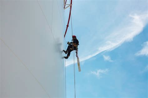 남성 작업자 다운 높이 탱크 쉘 플레이트 로프 사다리 액세스 두께 저장 탱크 가스 프로판의 안전 검사 프리미엄 사진