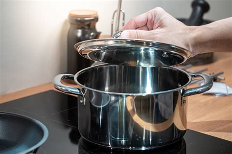 쇼핑 주방 용품 개념 남성의 손이 스테인리스 냄비를 열고 주방용품 쇼룸 매장의 전기 호브에 불을 붙였다 집에서 가정용 주방용 조리기구 구입 가열장치에 대한 스톡 사진 및