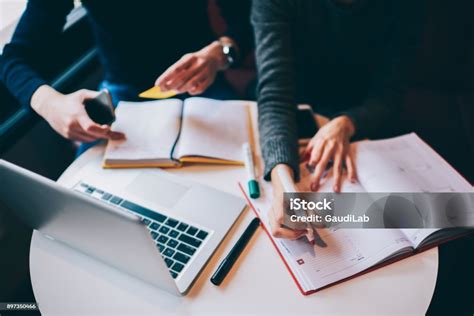 자른된 이미지의 여자의 실내 테이블에 앉아있는 동안 마커를 사용 하 여 메모장에 기록 정보를 손 여성 남성 동료 교과서에서 정보를 확인 하면서 작업 비즈니스 계획 만들기
