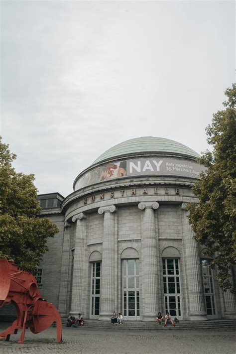 A Large Building With A Giant Red Object In Front Of It Photo Free