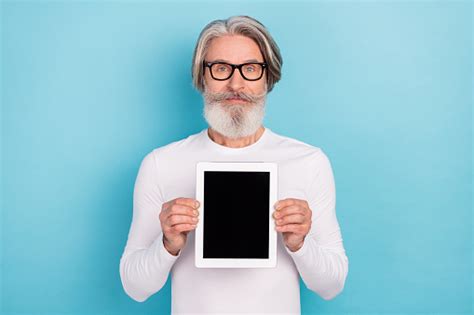 매력적인 콘텐츠 회색 머리 남자의 초상화 는 생생한 파란색 배경에 고립 된 광고 복사 공간을 보여주는 손 가젯에 들고 태블릿에 대한 스톡 사진 및 기타 이미지 Istock