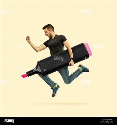 Man Jumping With Big Pink Marker On Yellow Background Copyspace For
